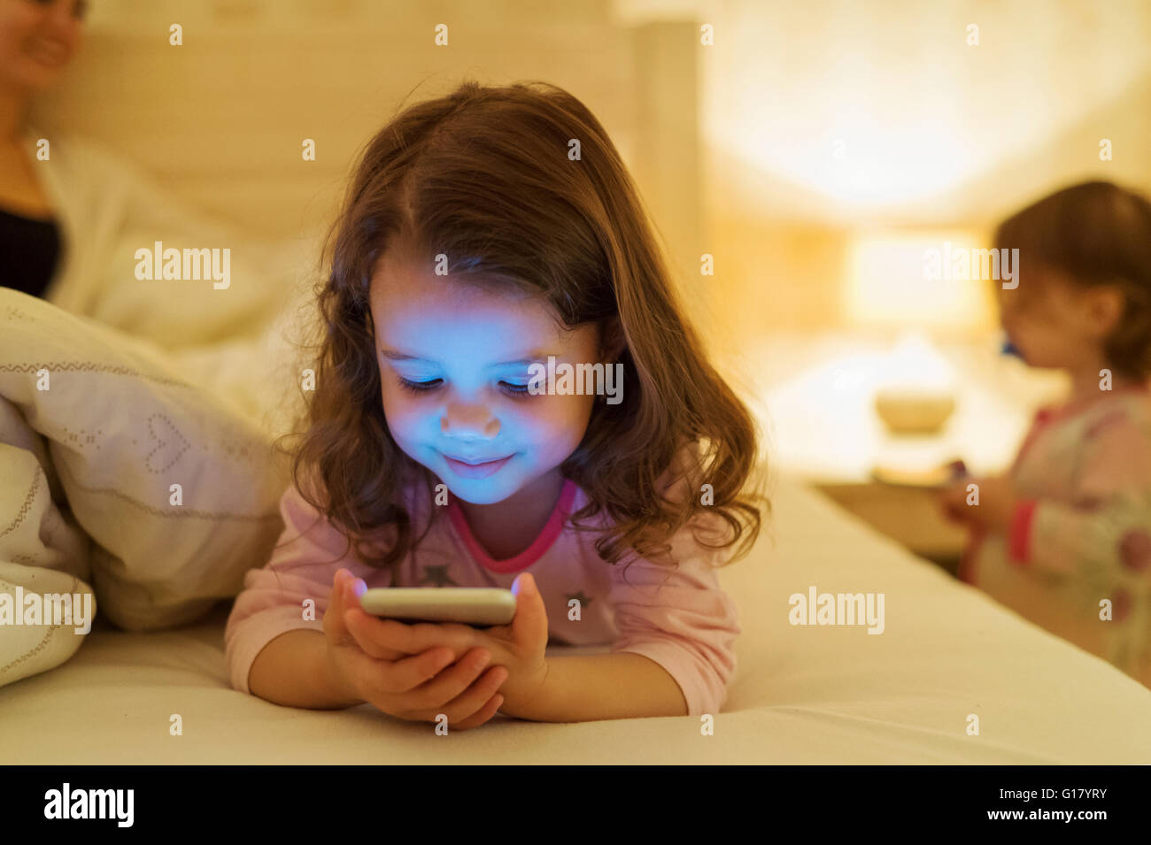 Little girl with smartphone lying in a bed, bedtime Stock Photo - Alamy