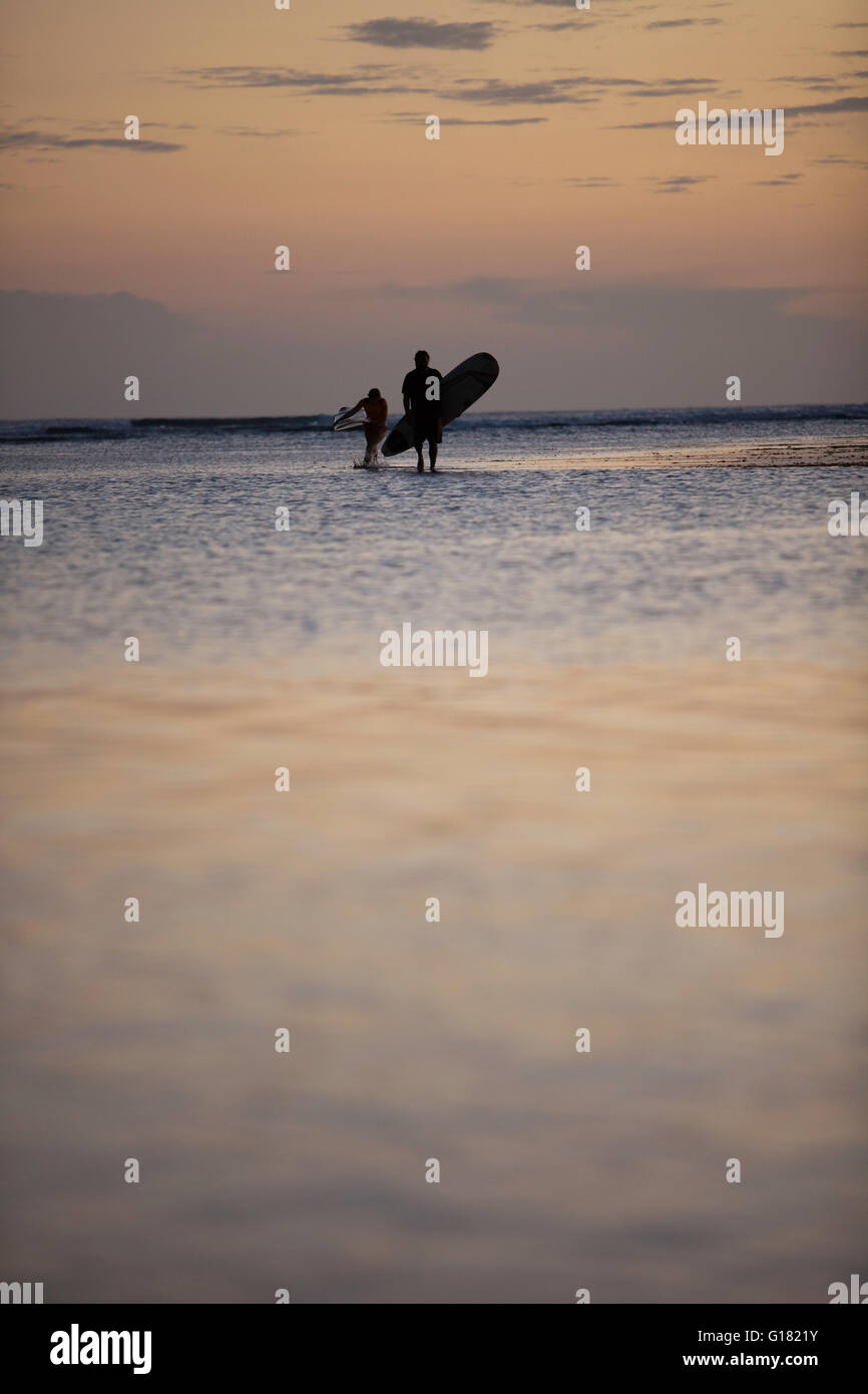 Surfers crossing reef at Ala Moana, sunset Stock Photo - Alamy