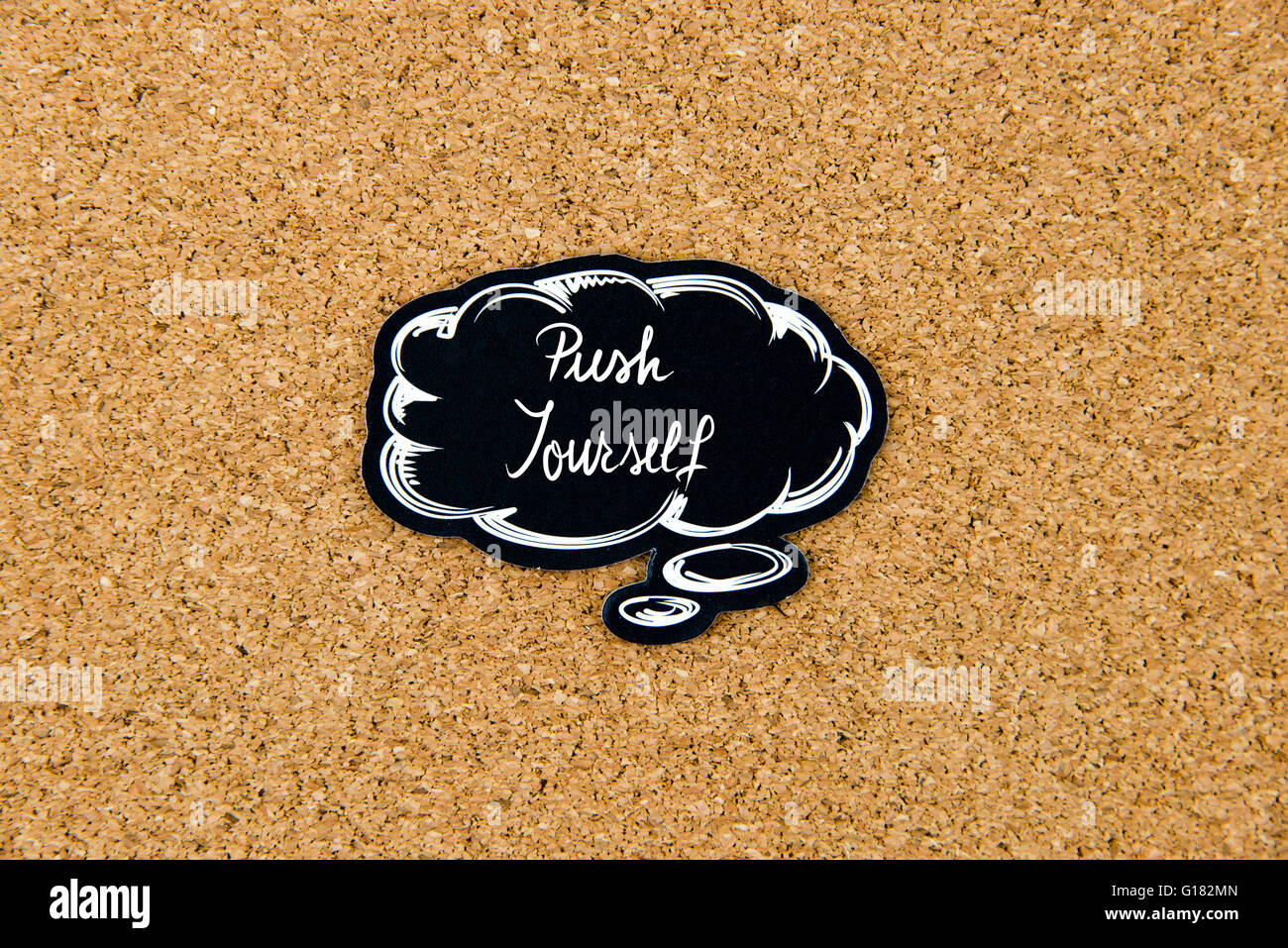 PUSH YOURSELF written on black thinking bubble over cork board ...