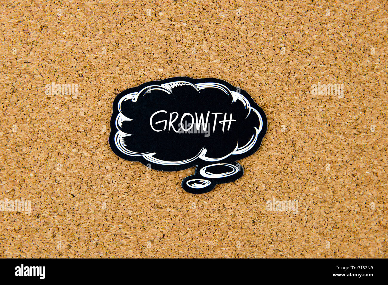 GROWTH written on black thinking bubble over cork board background ...
