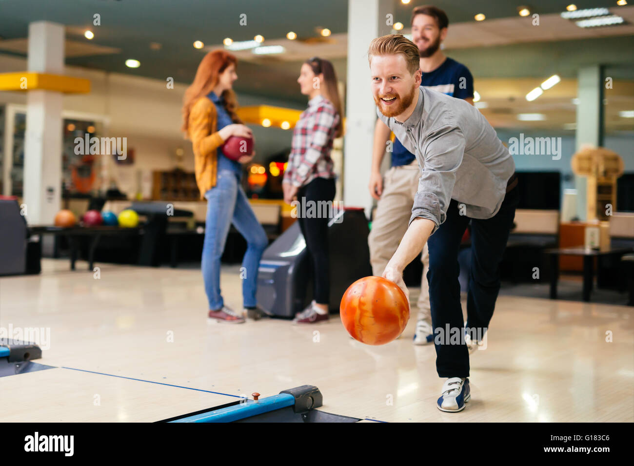 Happy people enjoying bowling together Stock Photo - Alamy