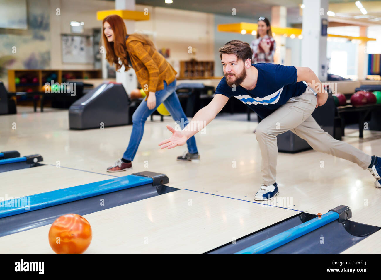 Happy people enjoying bowling together Stock Photo - Alamy