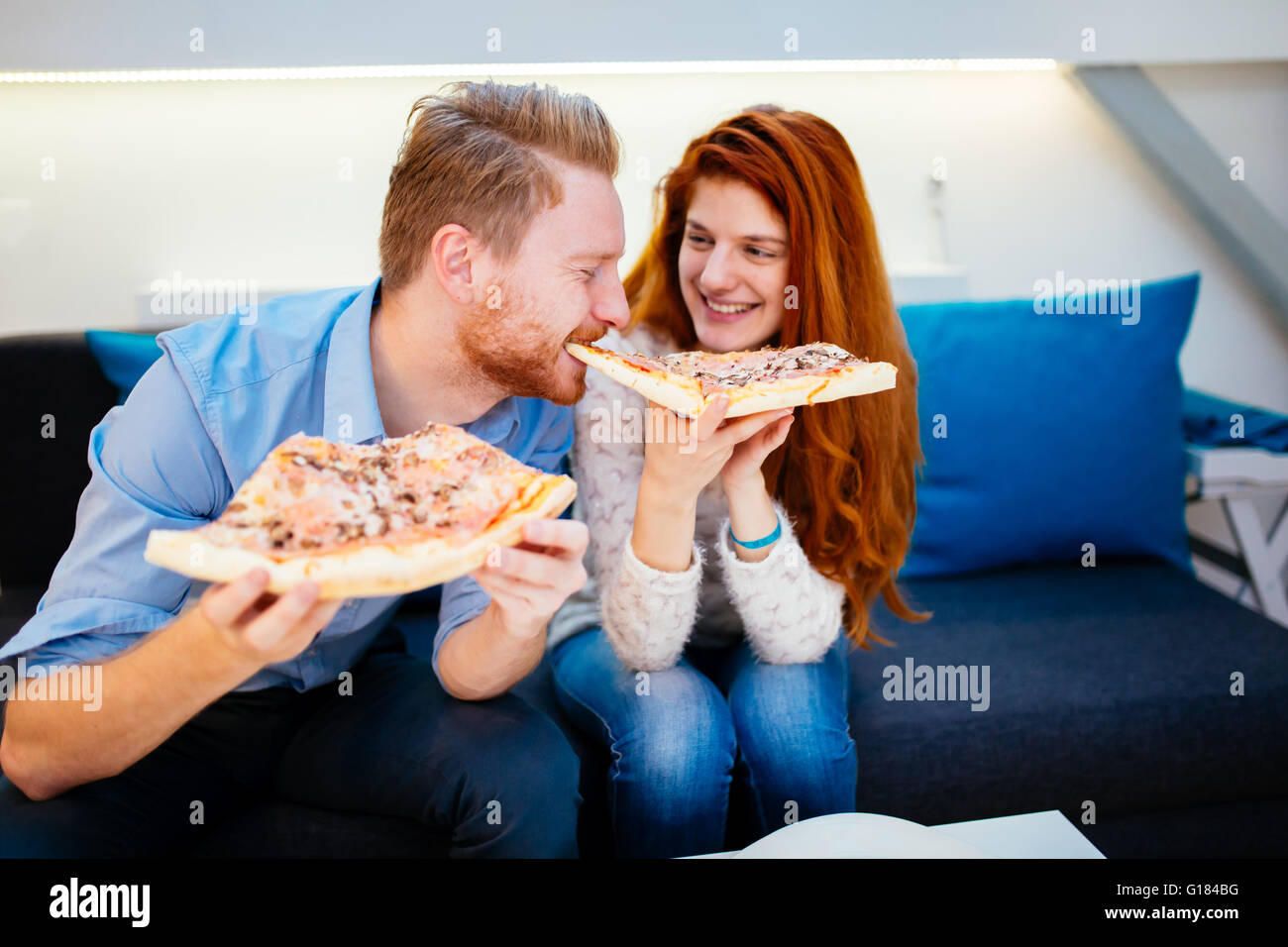 Couple sharing pizza and eating together happily Stock Photo - Alamy