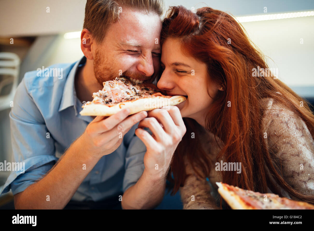 Couple sharing pizza and eating together happily Stock Photo - Alamy