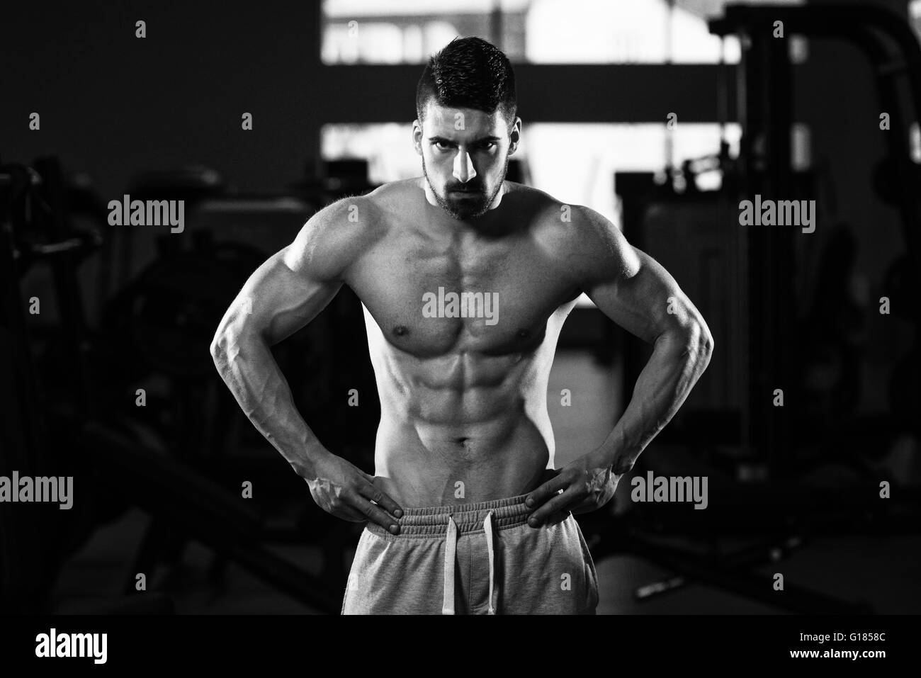 Young Man Standing Strong In The Gym And Flexing Muscles - Muscular ...
