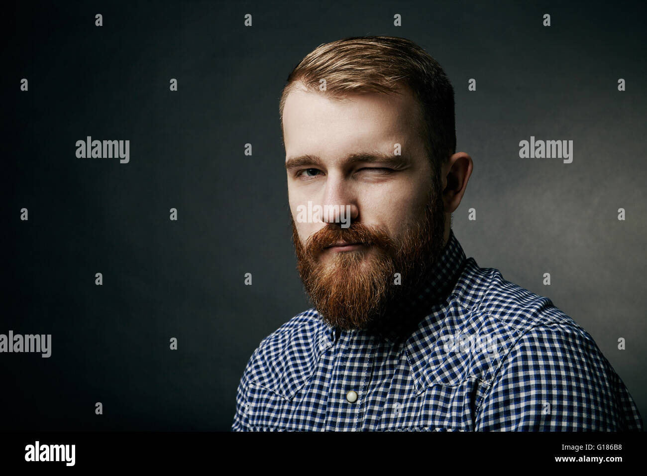 Winking red bearded man studio portrait on dark background Stock Photo ...
