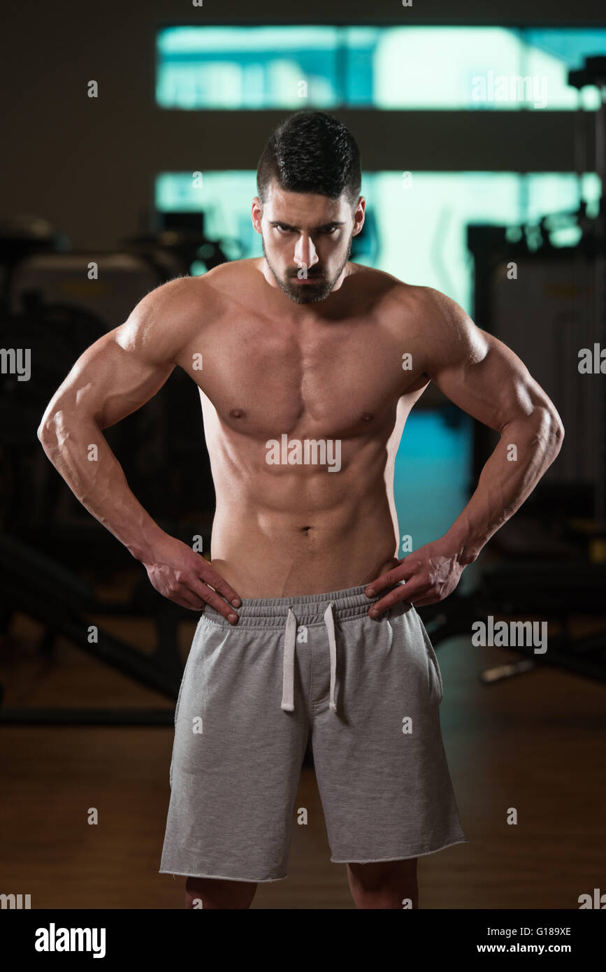 Young Man Standing Strong In The Gym And Flexing Muscles - Muscular ...