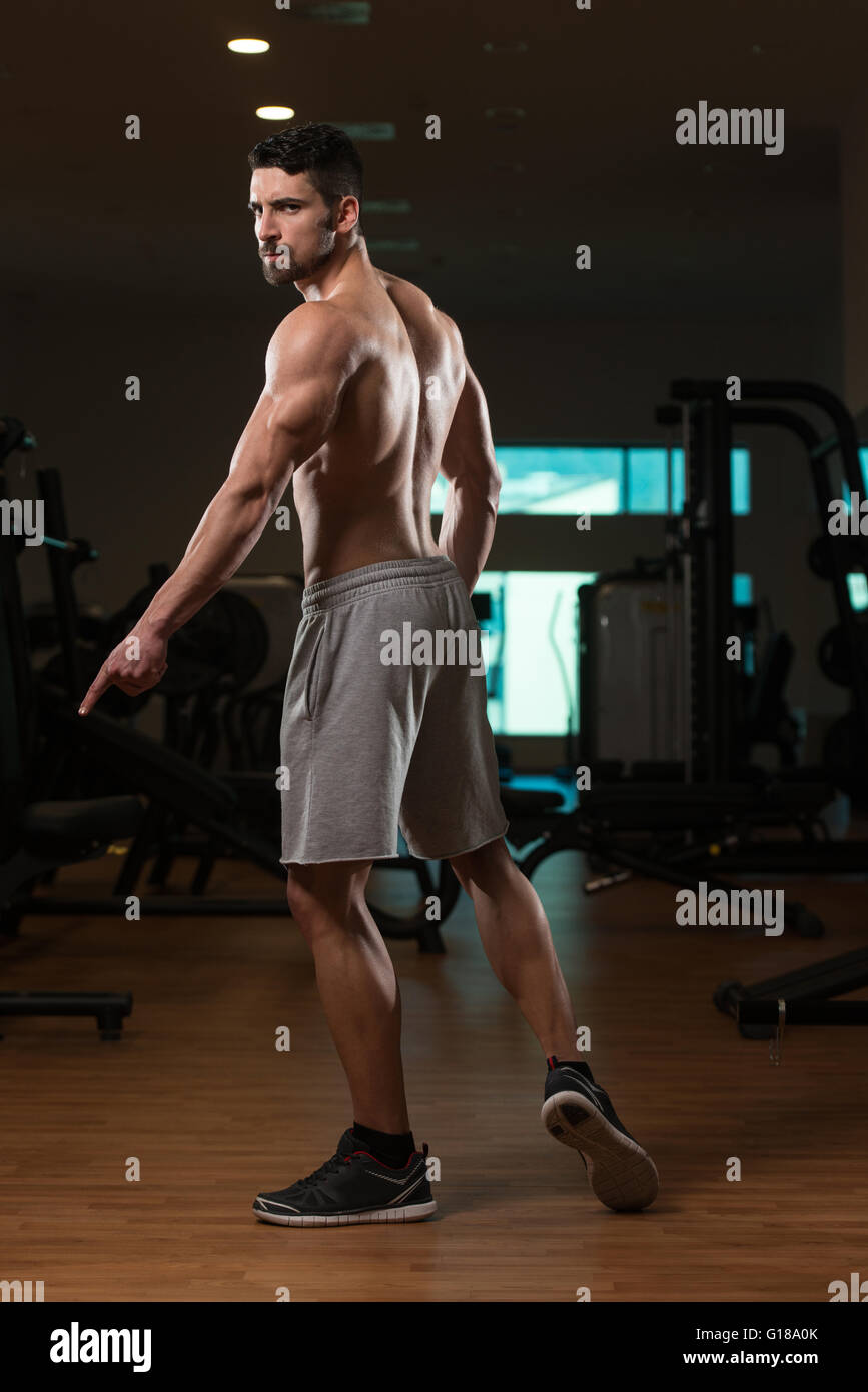 Young Man Standing Strong In The Gym And Flexing Muscles - Muscular ...