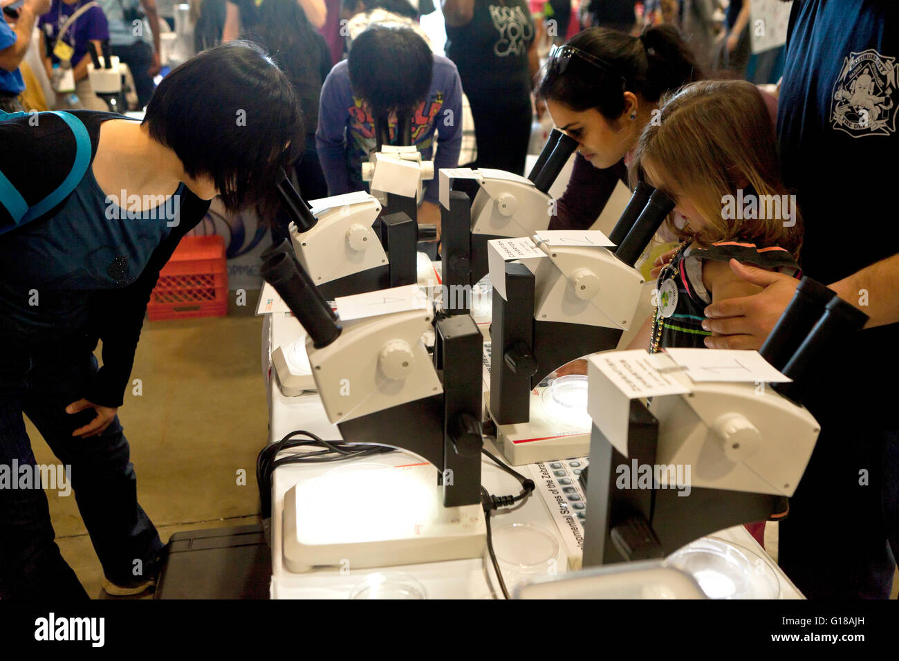 People looking through microscope at science fair - USA Stock Photo - Alamy