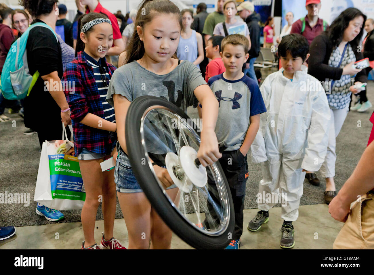 Young girl learning physics of gyroscope with a bicycle wheel at a ...
