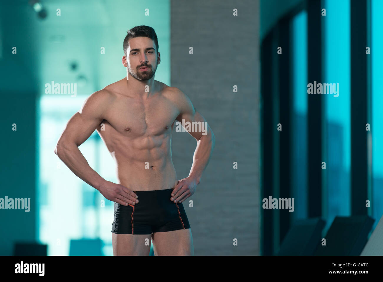 Young Muscular Man Flexing Muscles By Swimming Pool And Sun Loungers ...