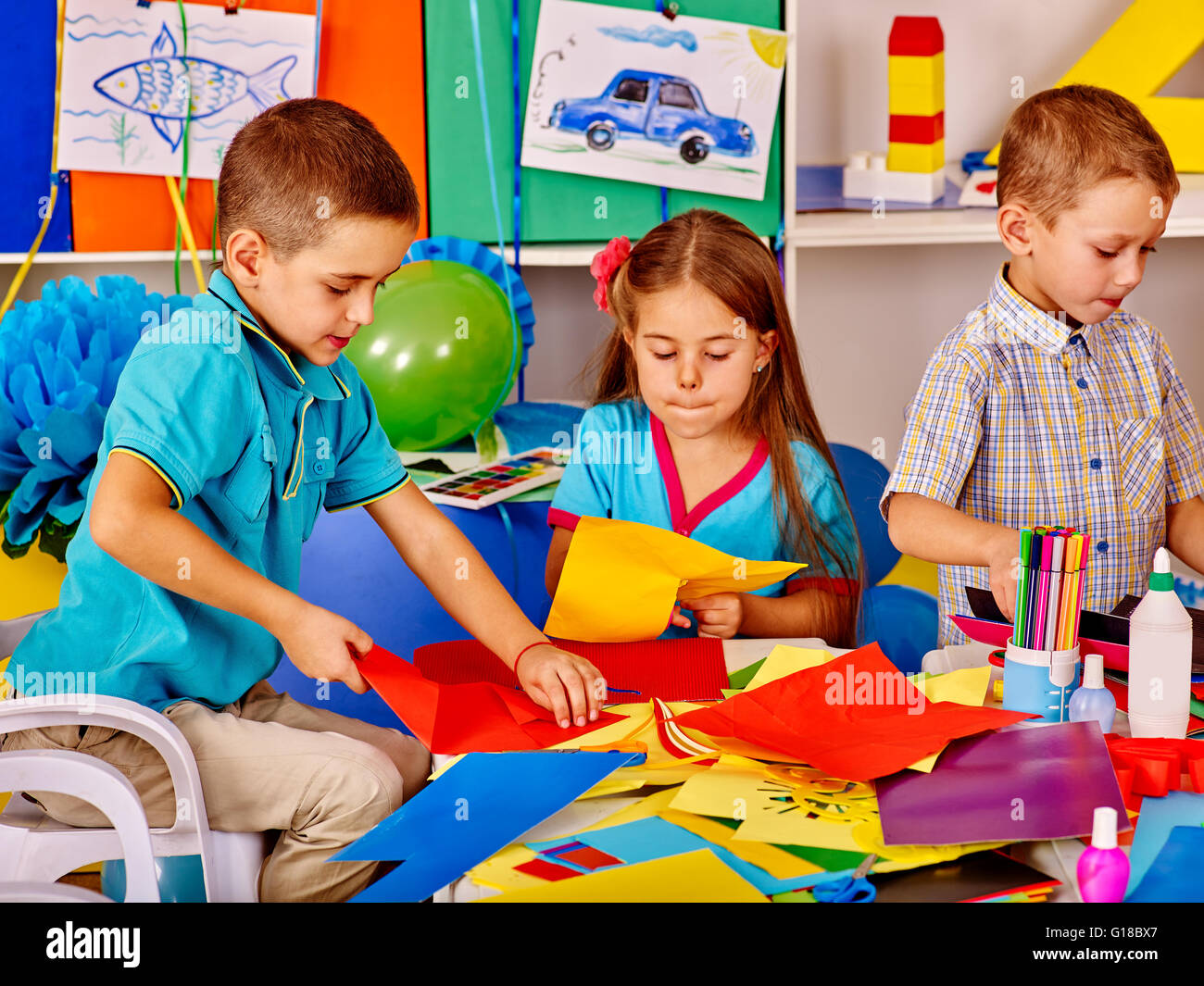 Kids holding colored paper on table in kindergarten Stock Photo - Alamy