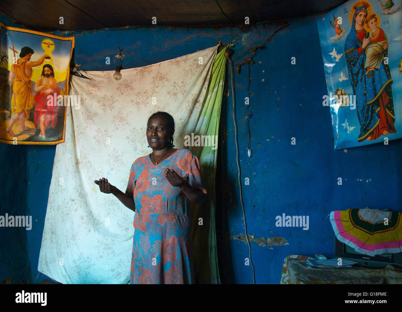 Woman inside her house decorated with religious posters, Omo valley ...