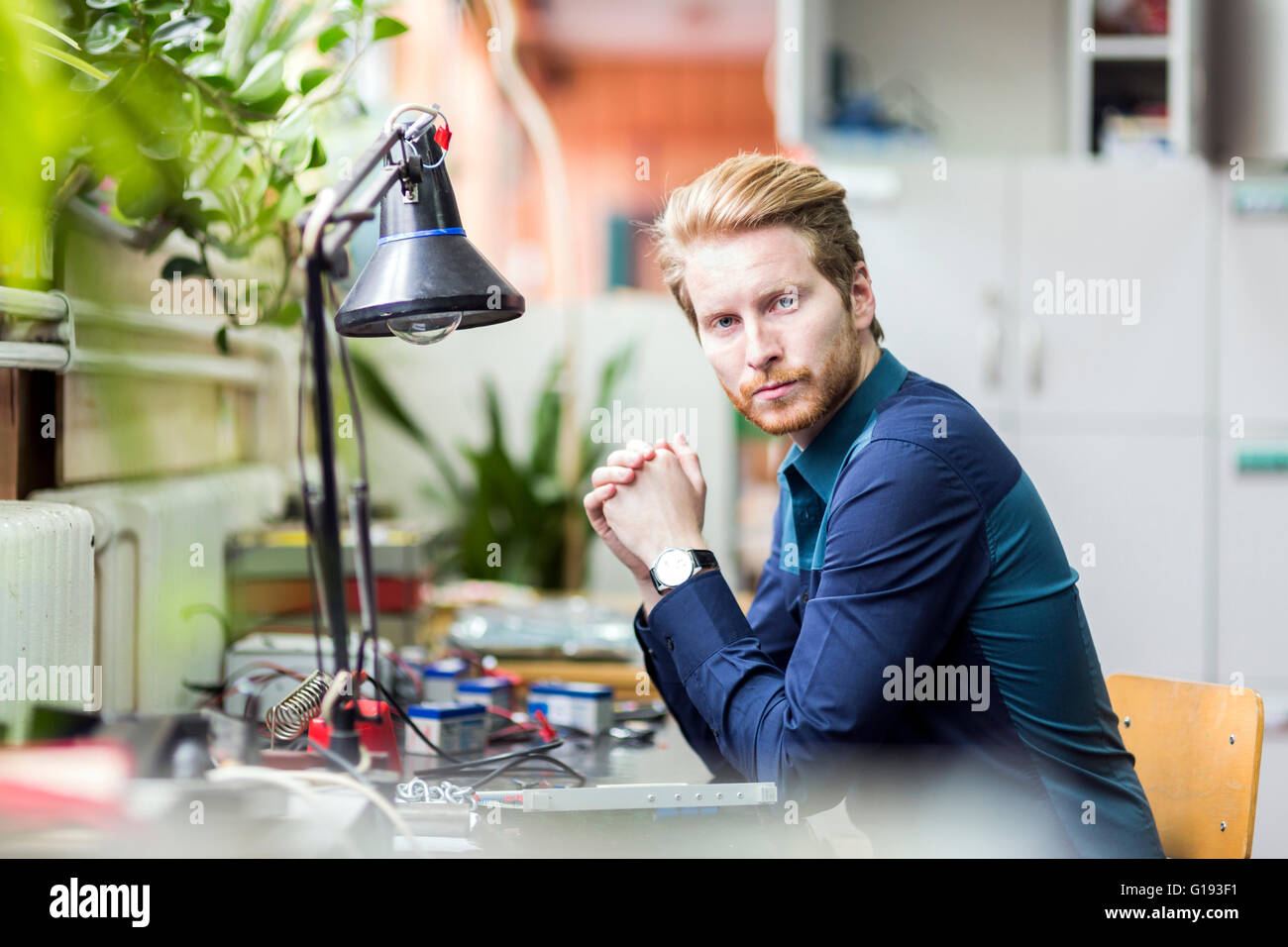 Young handsome man thinking how to solder the circuit board and fix it ...