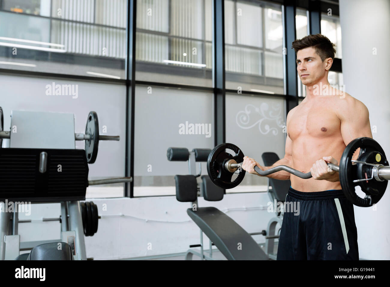 Muscular man bodybuilding in gym, lifting weights Stock Photo - Alamy
