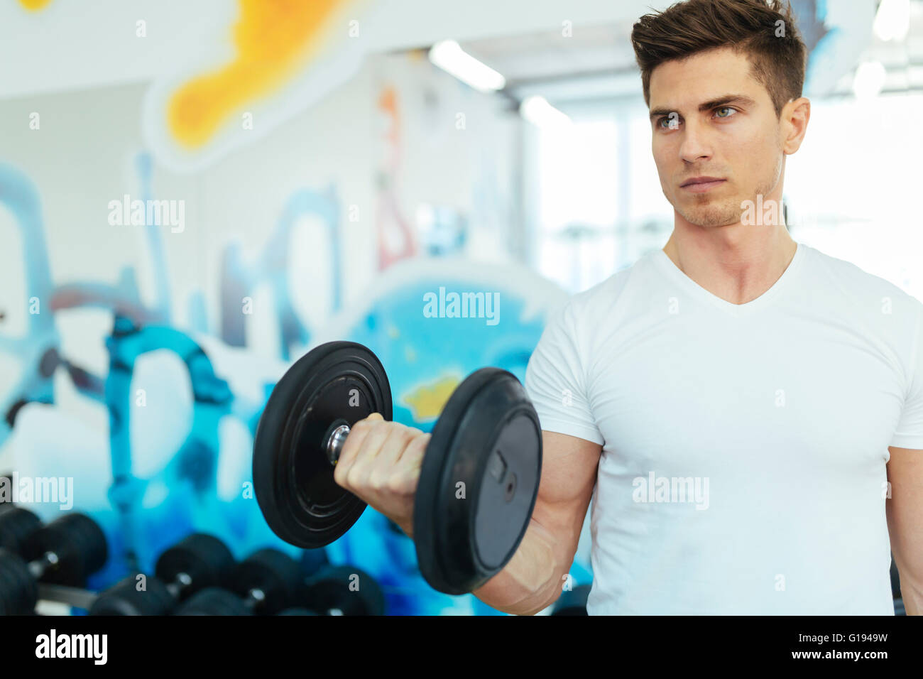 Handsome man lifting weights in gym and staying fit Stock Photo - Alamy