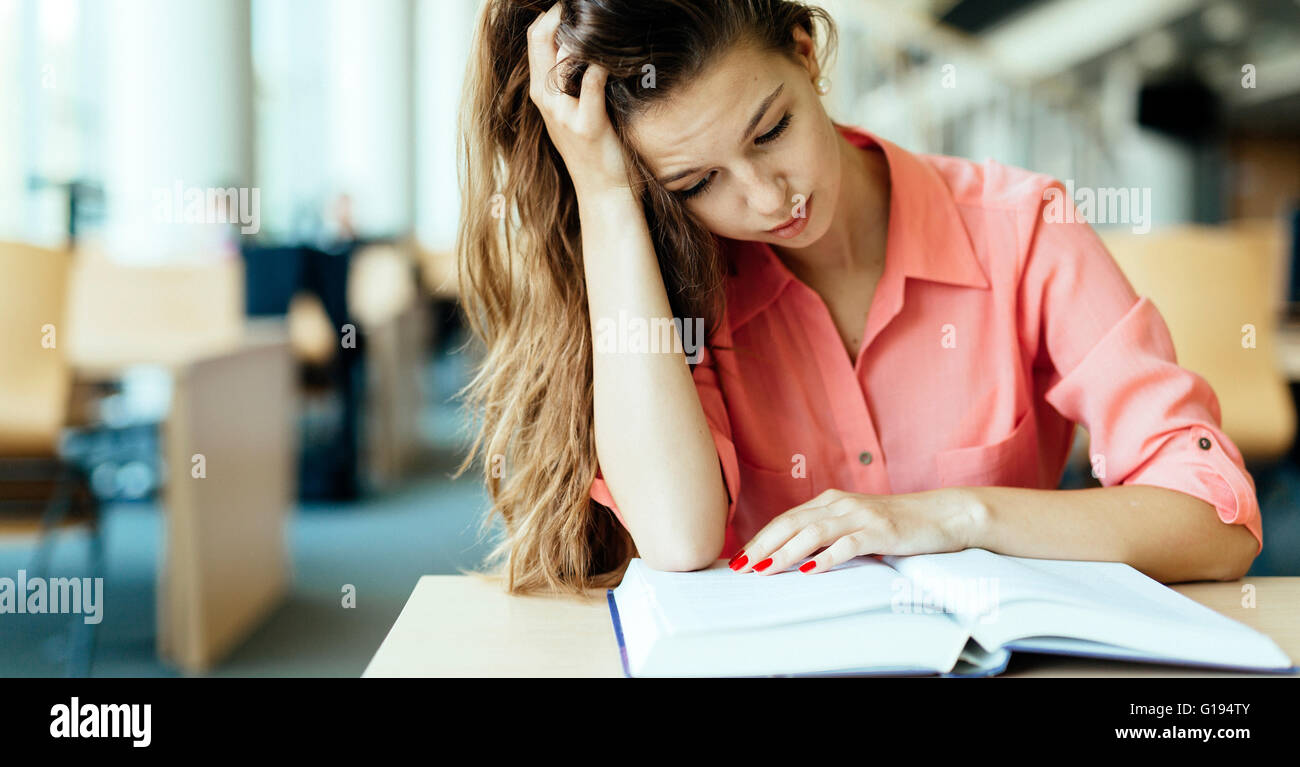 Female student studying and reading in a library but is having a hard ...