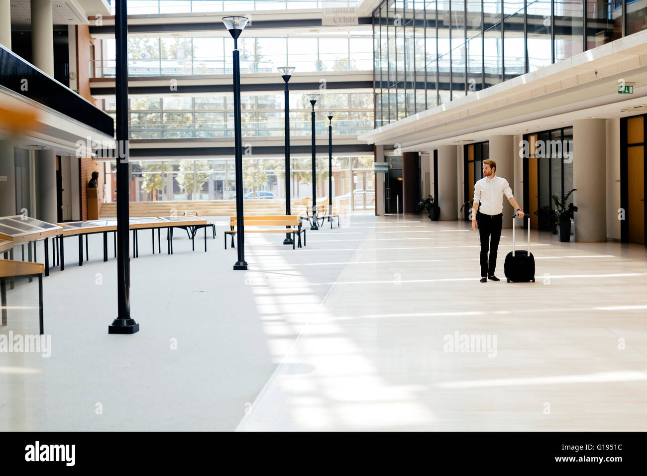 Handsome business holding a trolley and walking in a modern building ...