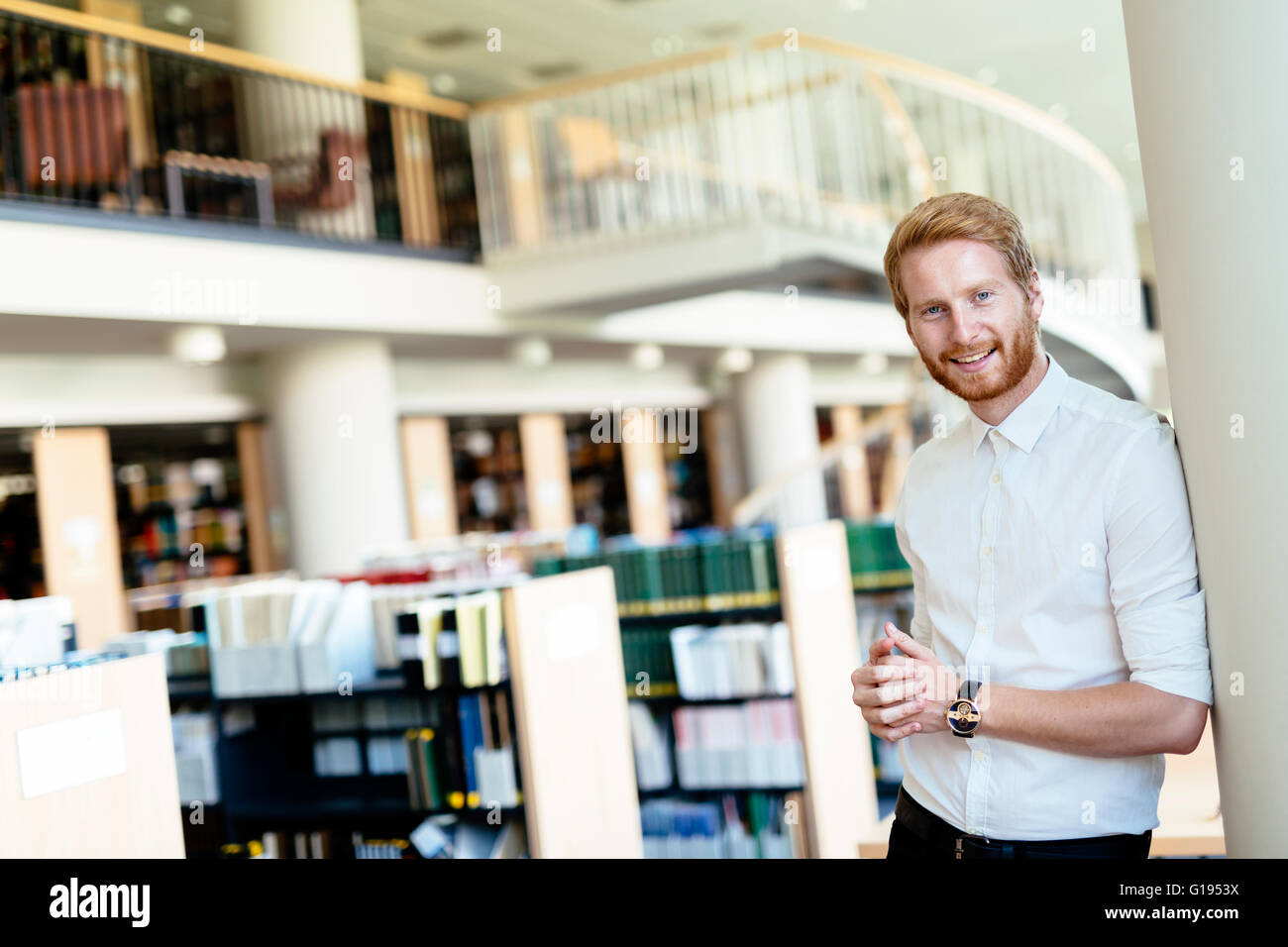 Handsome intelligent male student smiling in library Stock Photo - Alamy