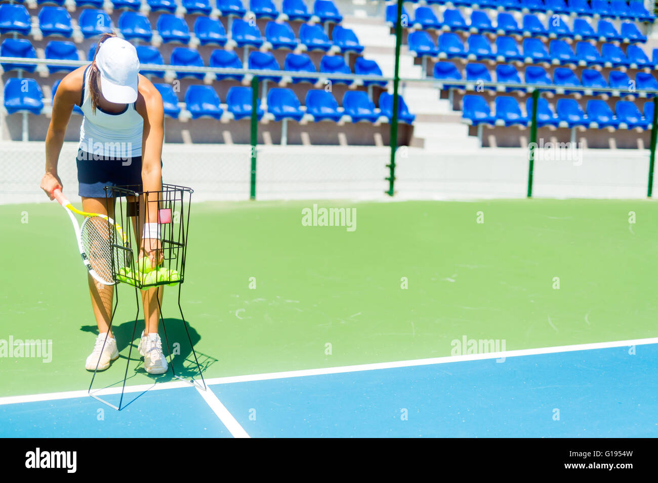 Female tennis player practicing service with the ball basket being at ...