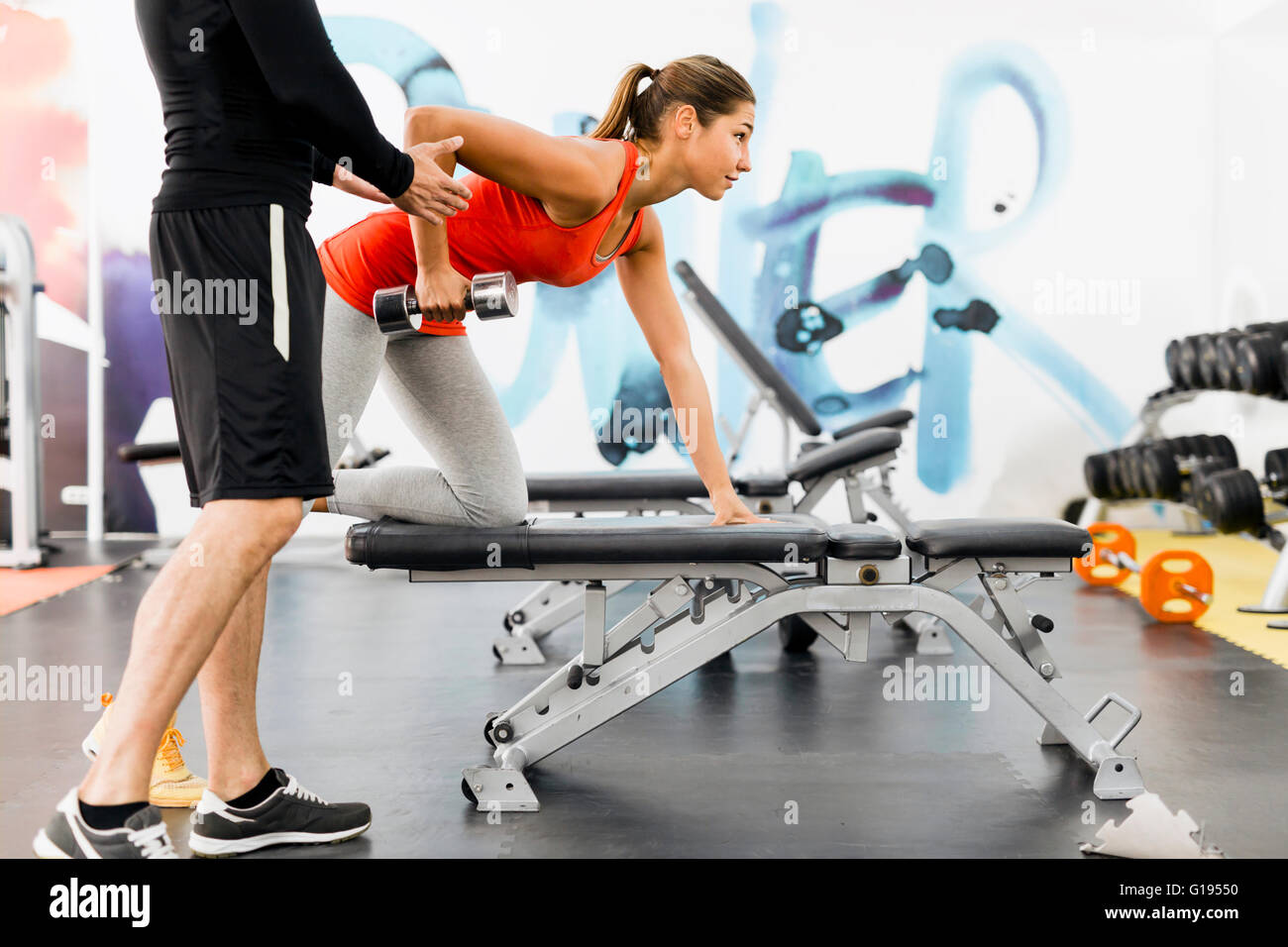 Young male trainer giving instructions to a woman in a gym and being ...