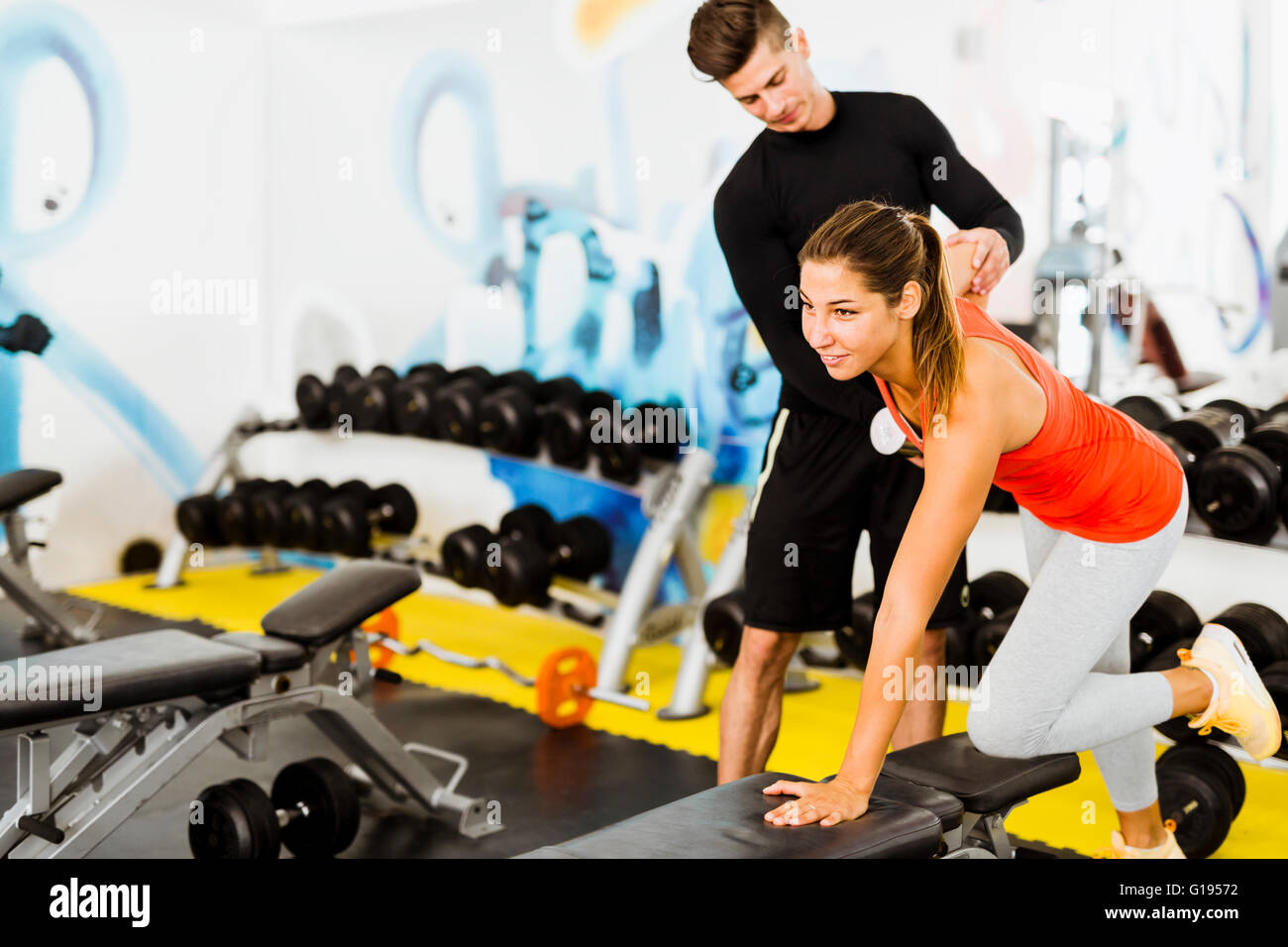 Young male trainer giving instructions to a woman in a gym and being ...