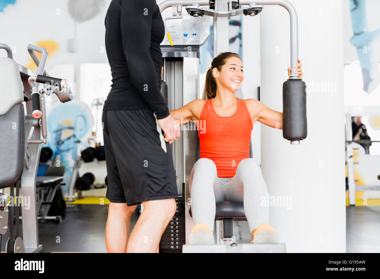Young male trainer giving instructions to a woman in a gym and being ...