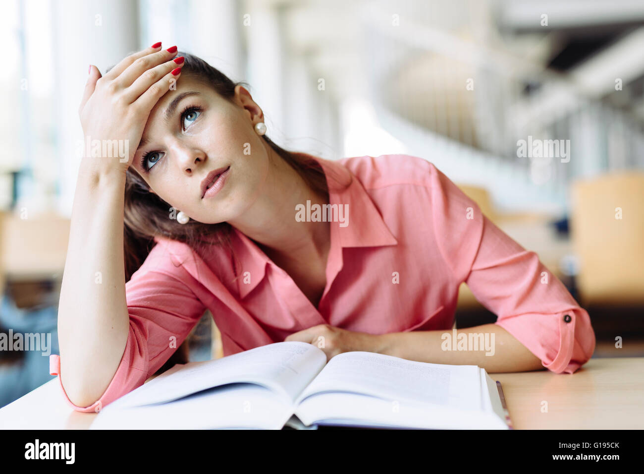 Female student studying and reading in a library but is having a hard ...