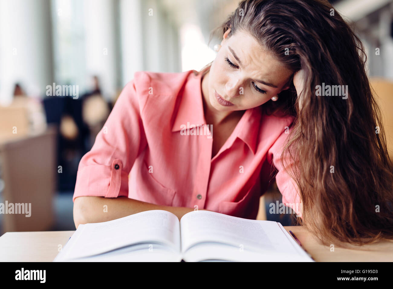 Female student studying and reading in a library but is having a hard ...