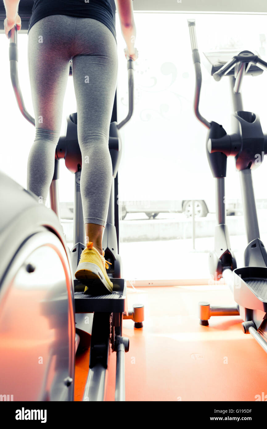 Closeup shot of legs of a female using elliptical trainer in a gym ...