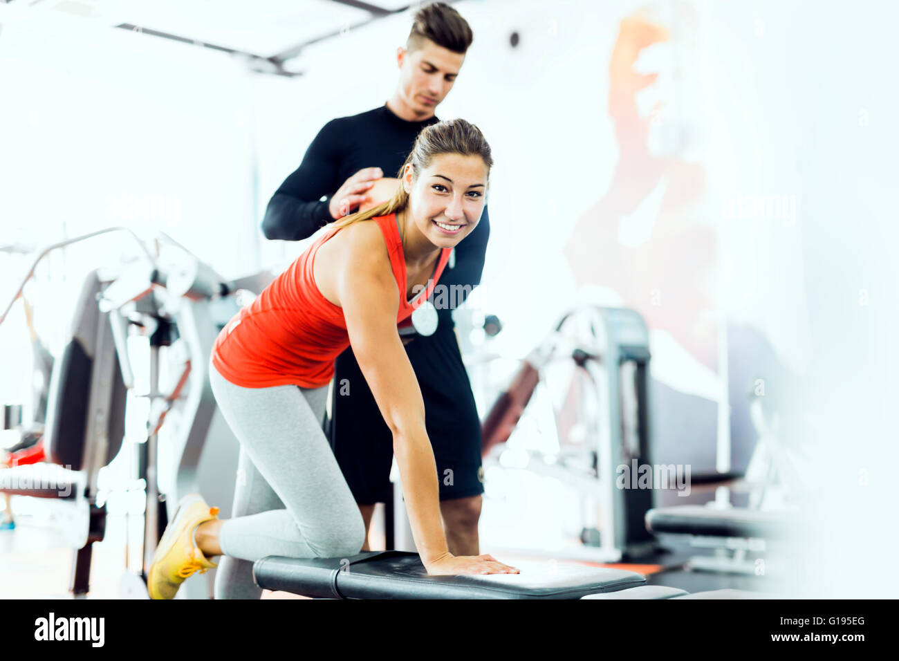 Young male trainer giving instructions to a woman in a gym and being ...