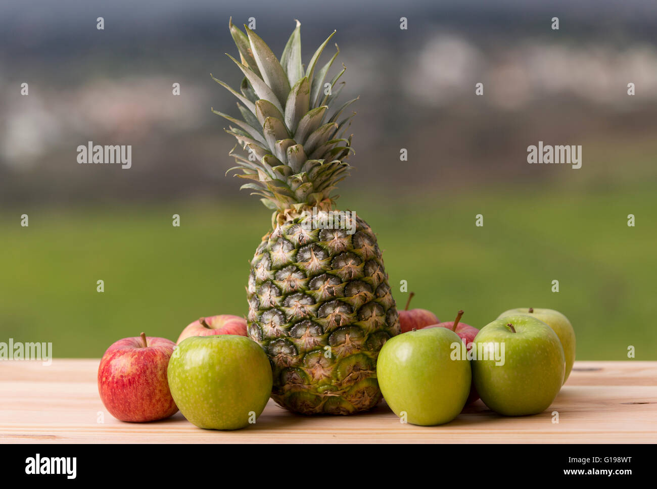 Pineapple and apple on wood table, outdoor Stock Photo - Alamy