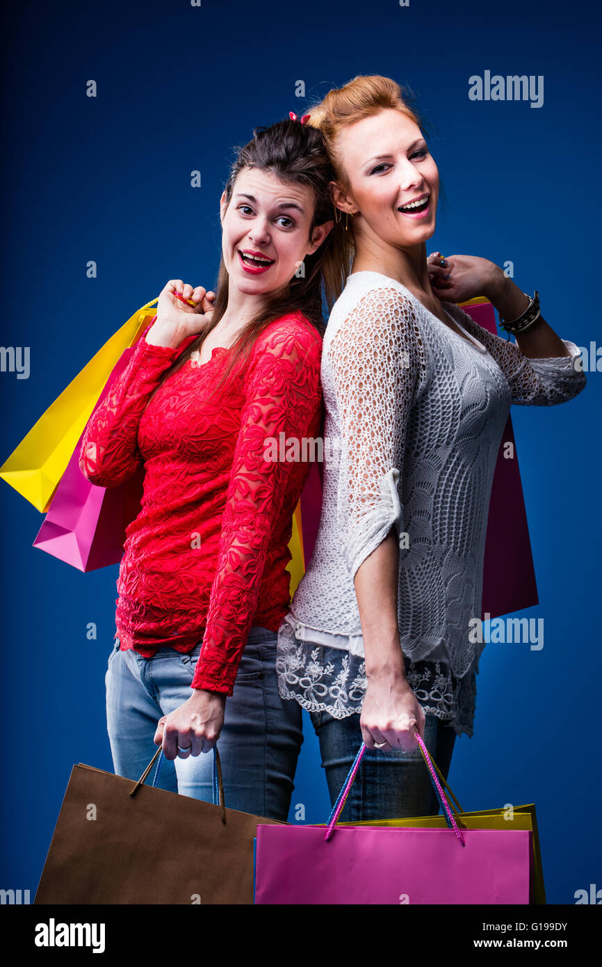 two women shopping with lots of colorful bags on blue background Stock ...
