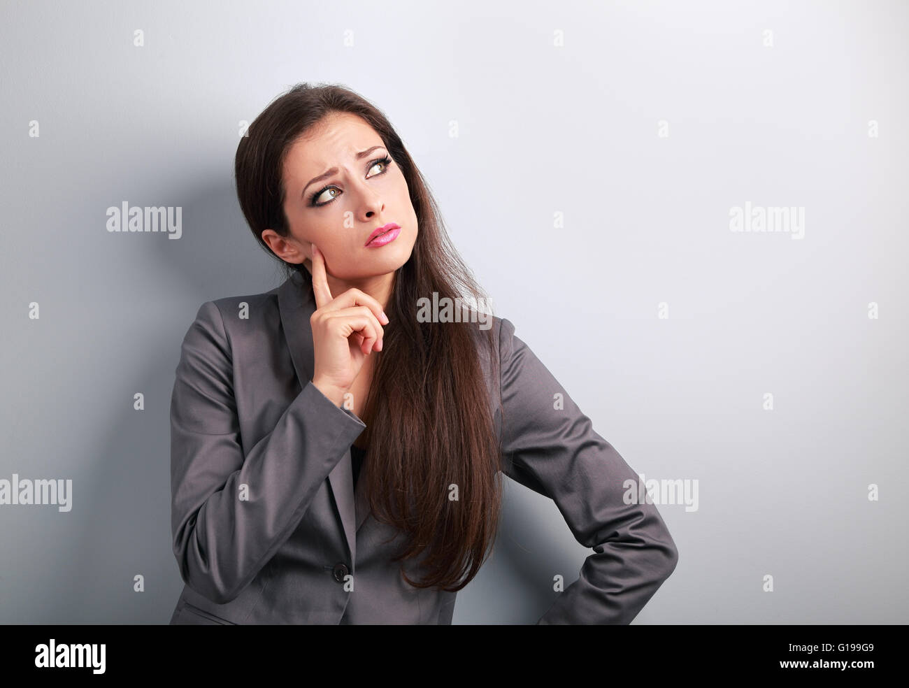 Thinking unhappy business woman in suit looking on blue empty copy space background Stock Photo ...