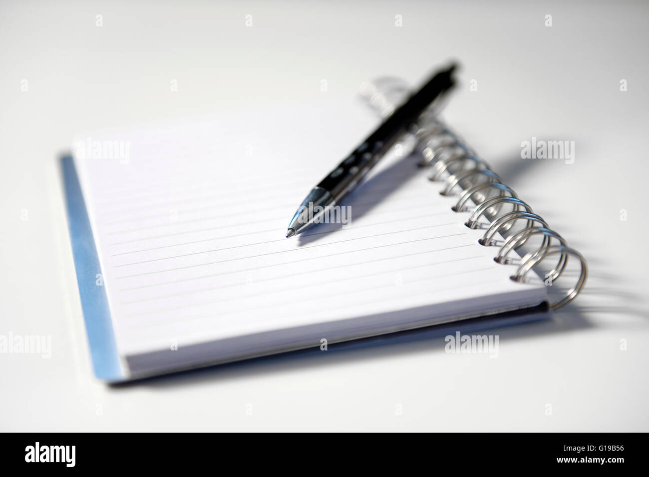 Spiral-bound lined notepad with a black pen resting on top, placed on a ...