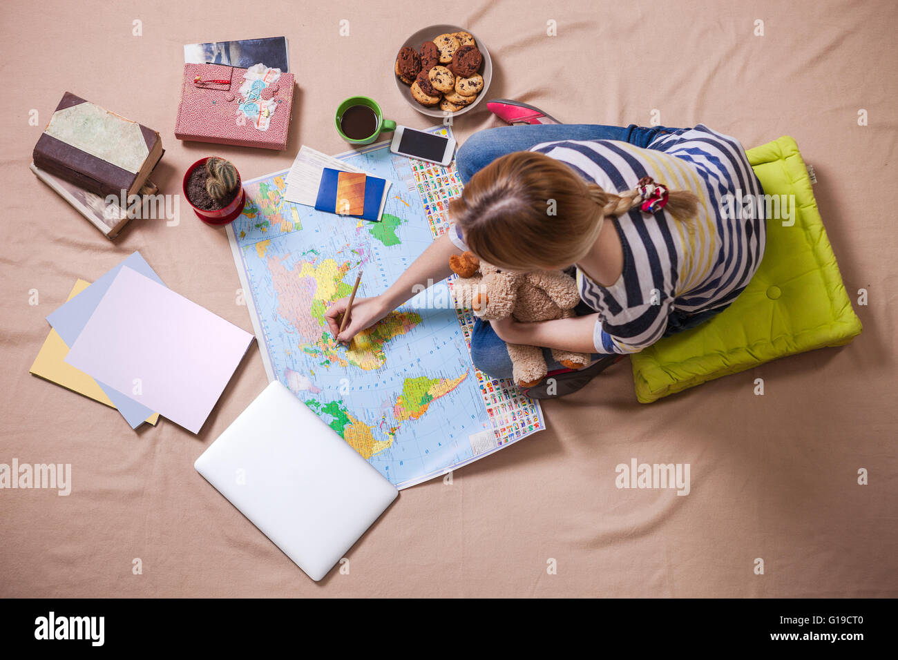 Young woman making marks on the map while sitting on the floor, view ...