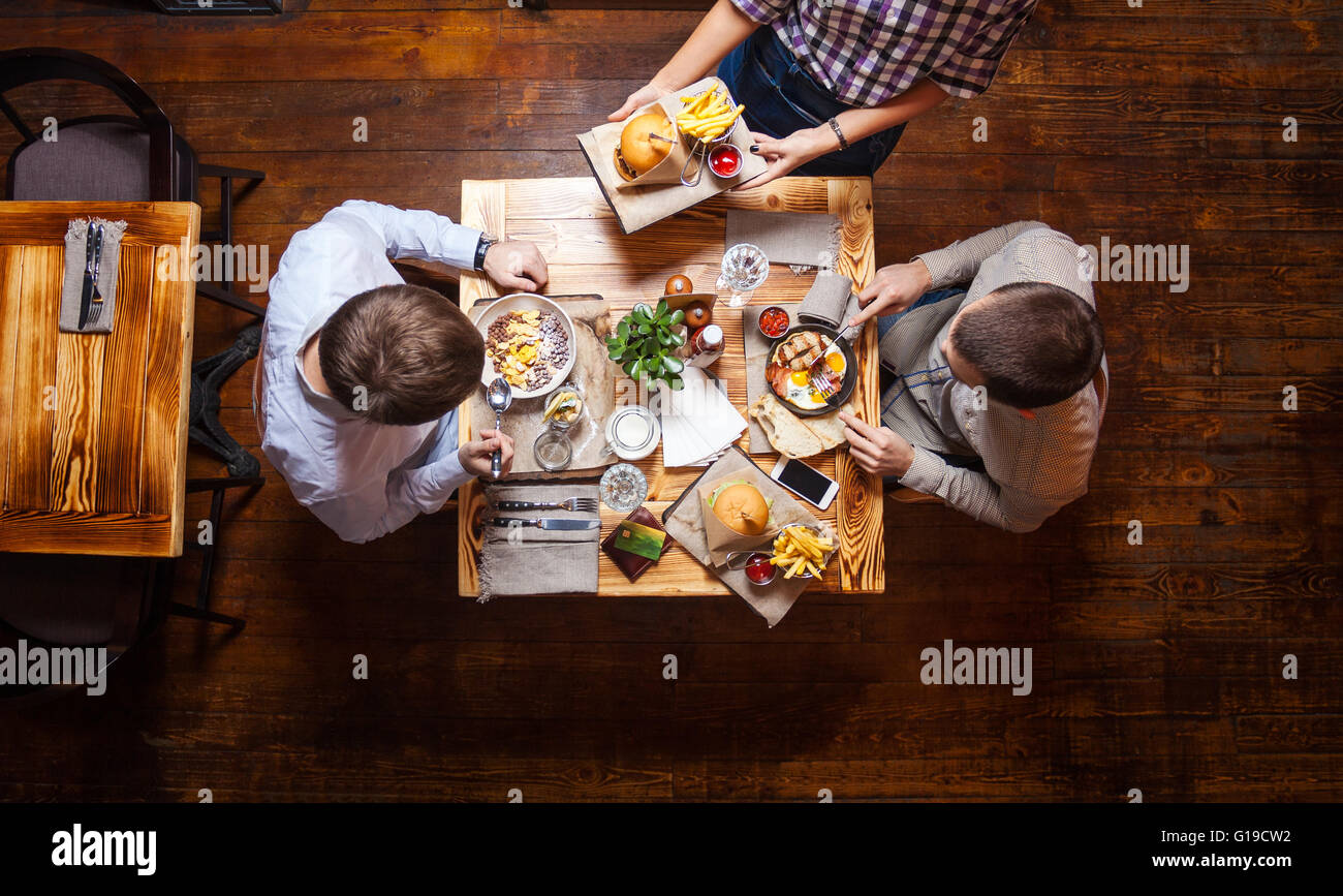 Young men having lunch at a cafe, view from above Stock Photo - Alamy