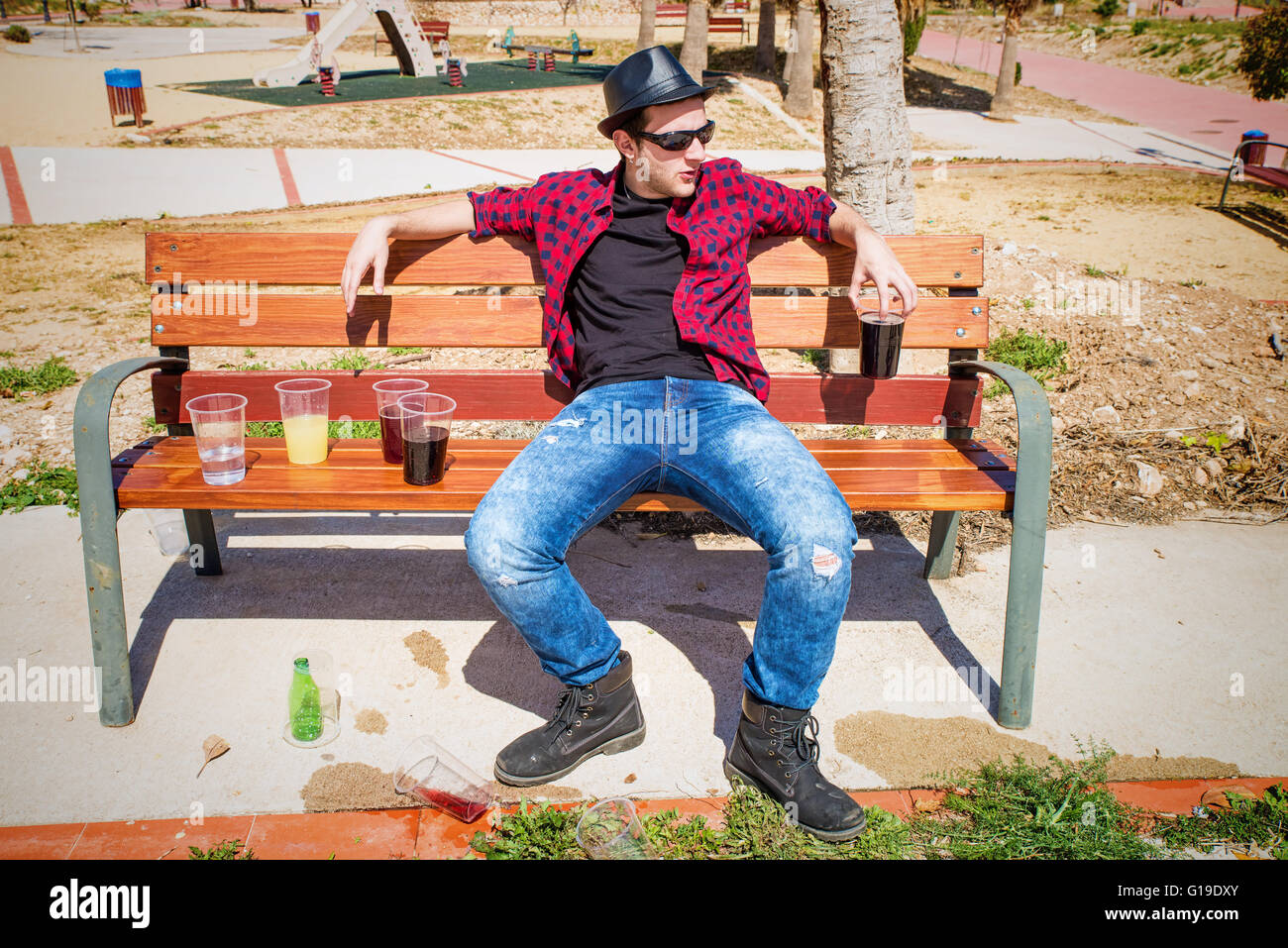 Guy getting heavily drunk on a park bench Stock Photo - Alamy