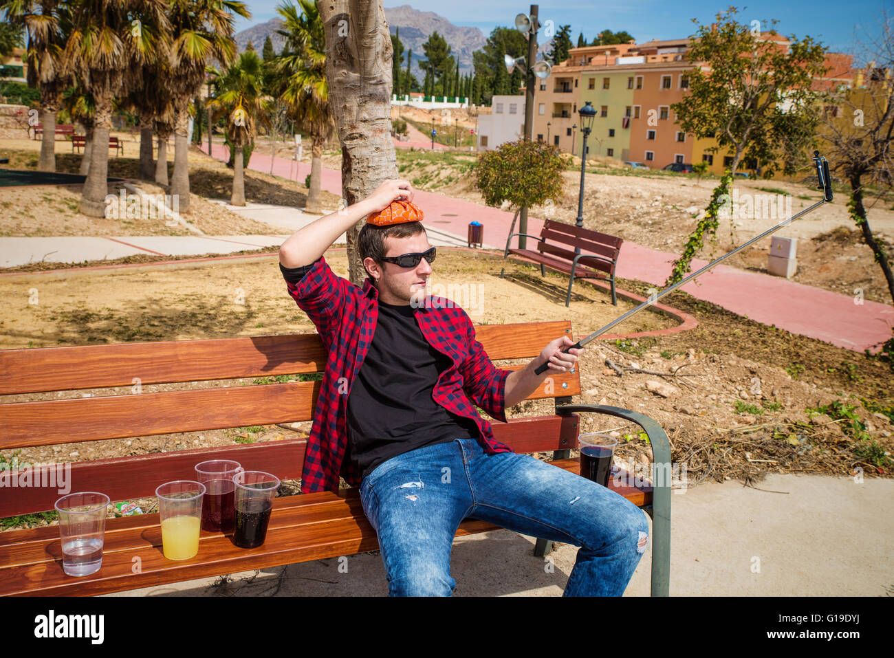 Guy documenting his hangover on a park bench with a selfie, a concept ...