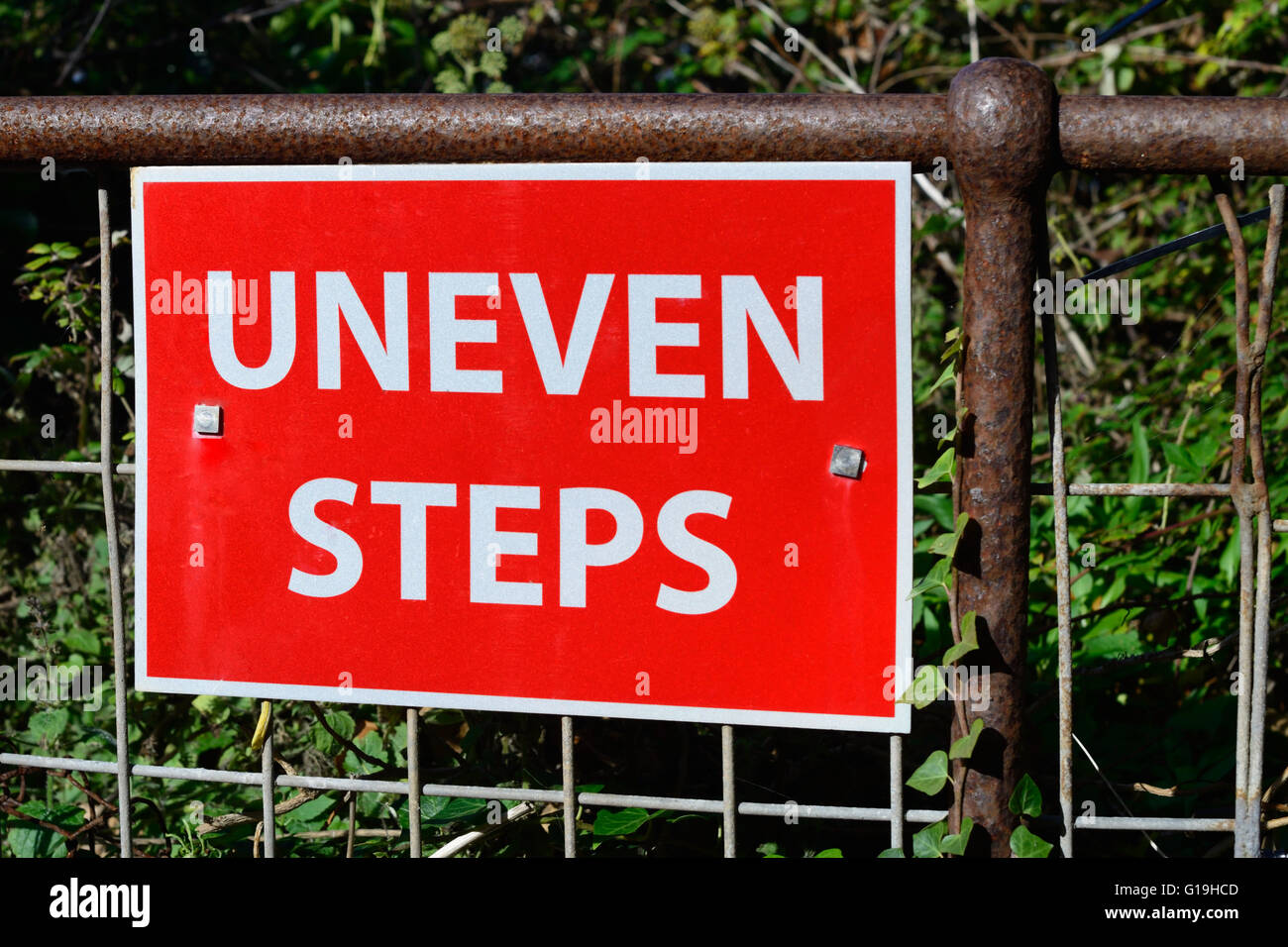 Sign warning about uneven steps Stock Photo - Alamy