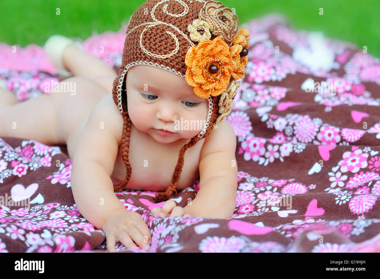 A happy young baby is sitting on green grass outside with bright Stock ...
