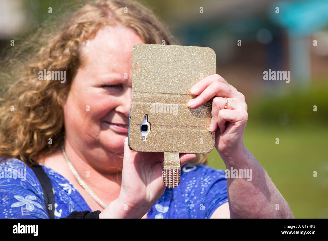 Woman taking photo with Smartphone in glittery gold case Stock Photo ...