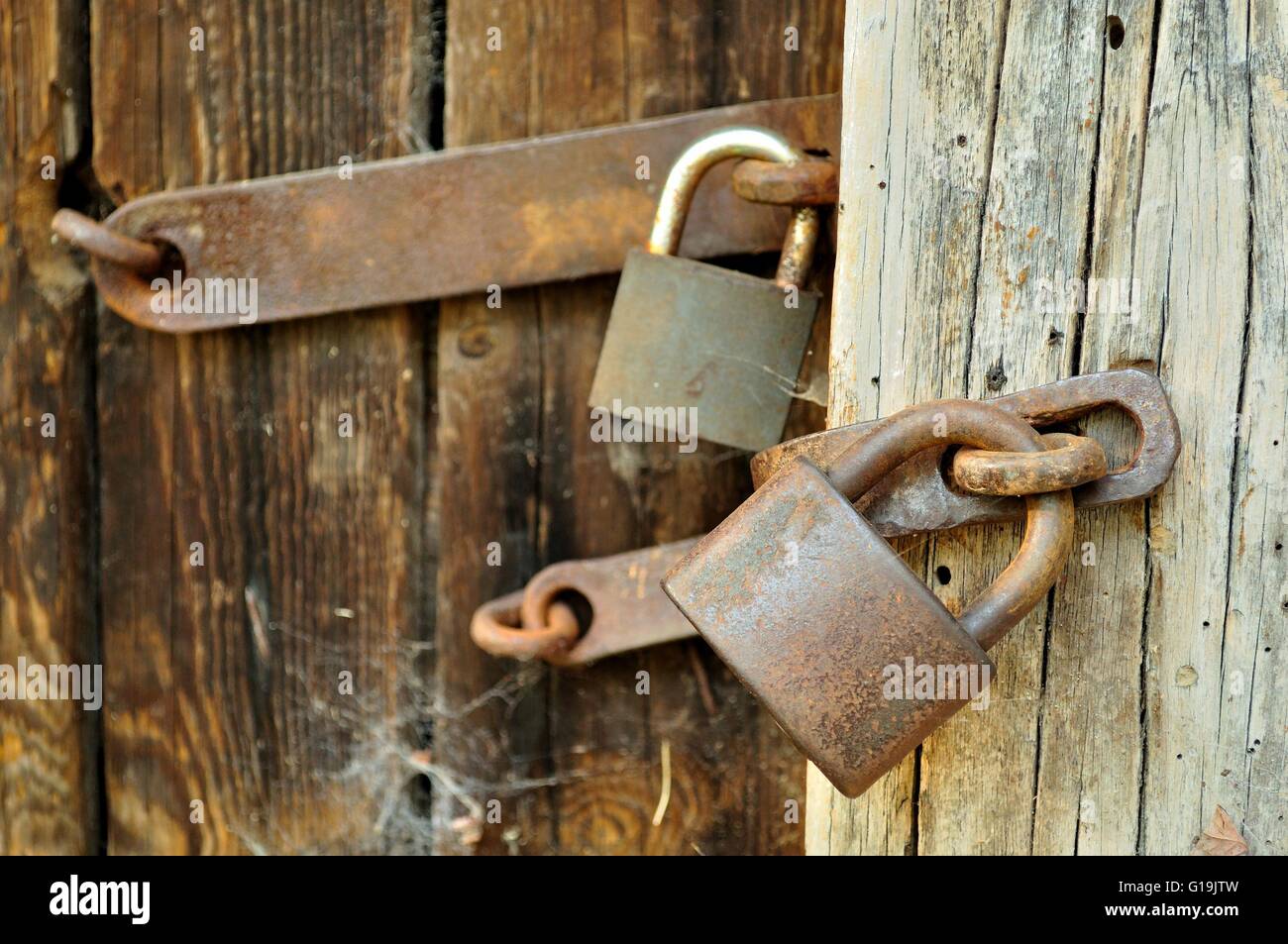 Two rusty padlock locking a wooden door Stock Photo - Alamy
