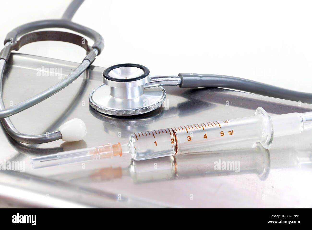 Beautiful stethoscope and glass syringe with reflection on tray ...