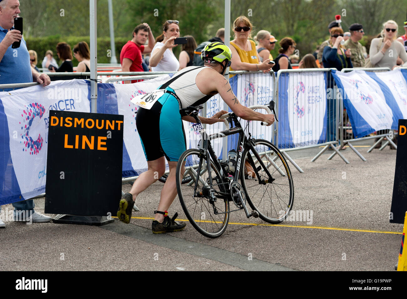 Cyclist dismounting at transition area in the Stratford Triathlon, UK ...