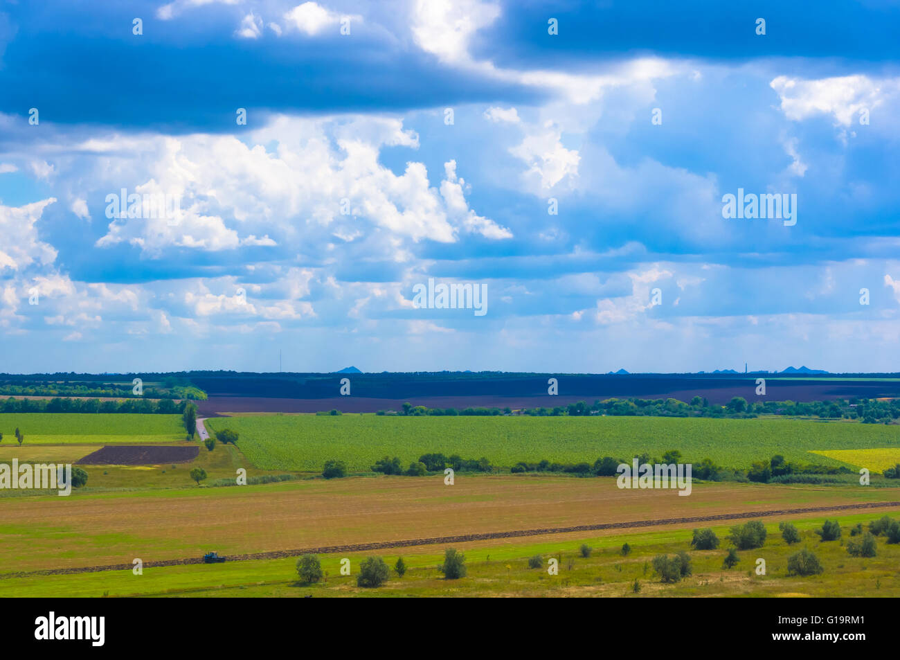 Summer landscape with green grass, village, fields and beautiful clouds ...