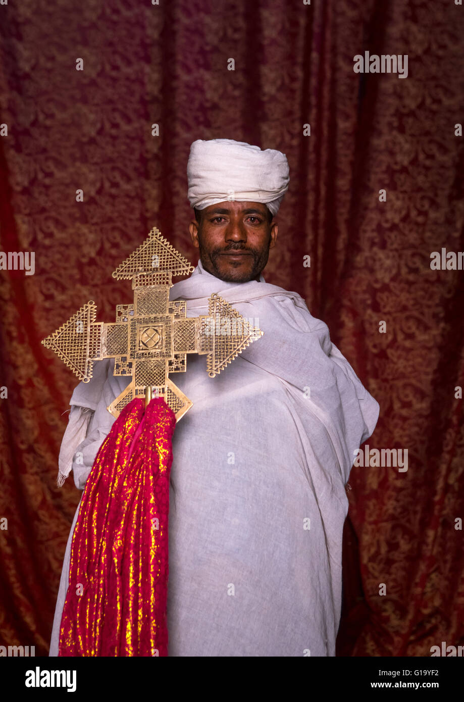 Portrait of an ethiopian orthodox priest holding a cross inside a rock ...