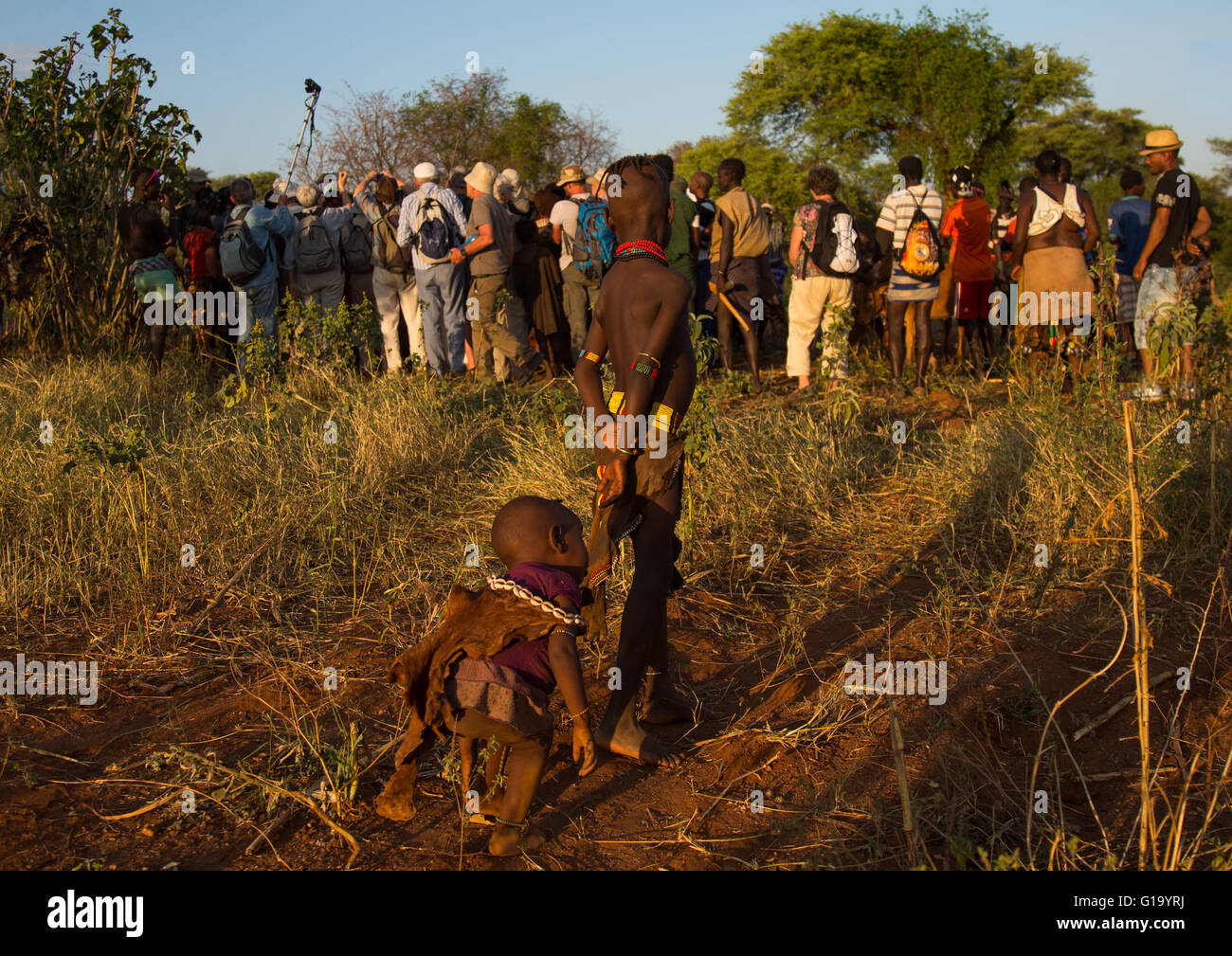 Hamer tribe children looking a group of tourists taking pictures of a ...