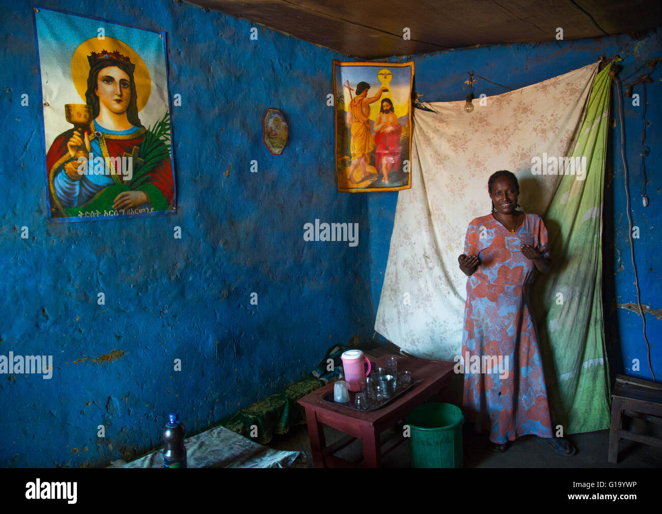Woman inside her house decorated with religious posters, Omo valley ...