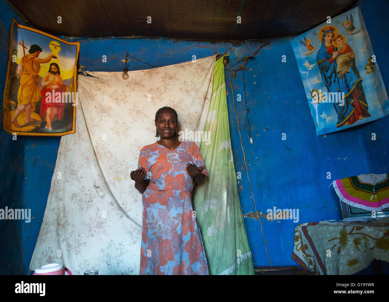 Woman inside her house decorated with religious posters, Omo valley ...